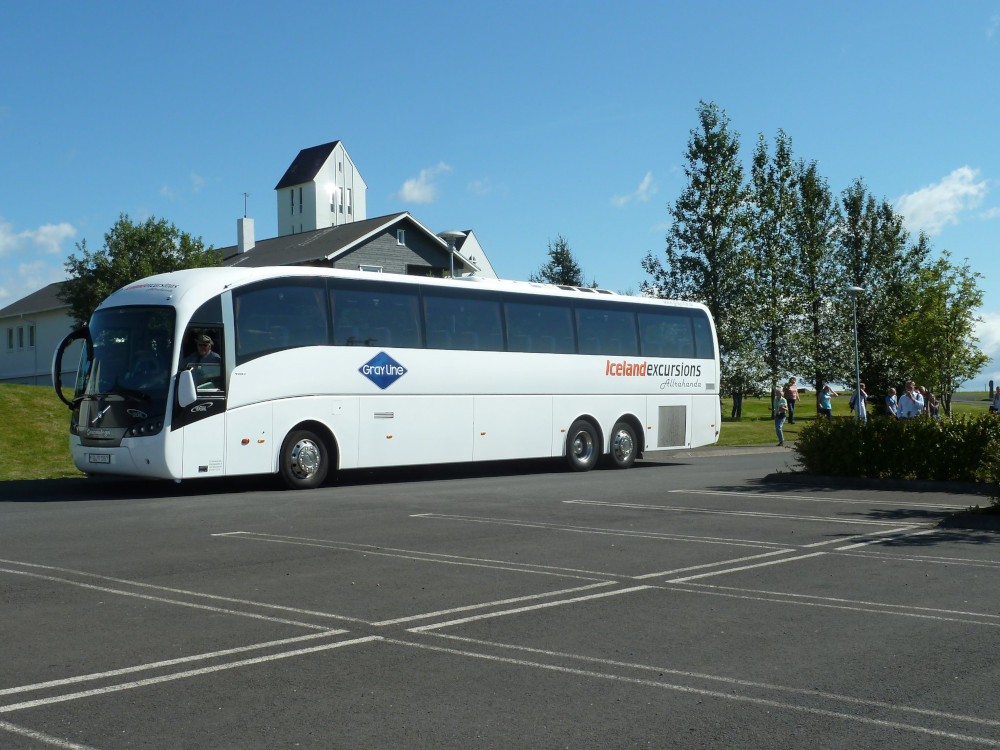 A Grayline coach, white and sleek, parked outside the church at ...