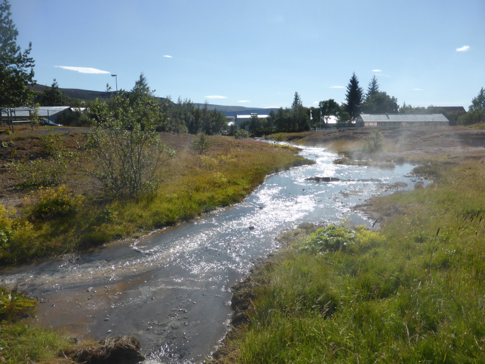 A hot river visibly steaming in the sun in the geothermal park at ...