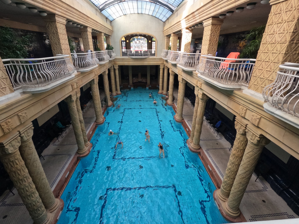 The pool at Gellert, a beautiful blue pool surrounded by yellow stone ...