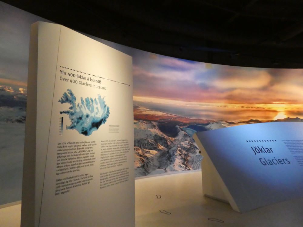 The glaciers exhibit. A curved wall has a huge picture of a sunset over ...
