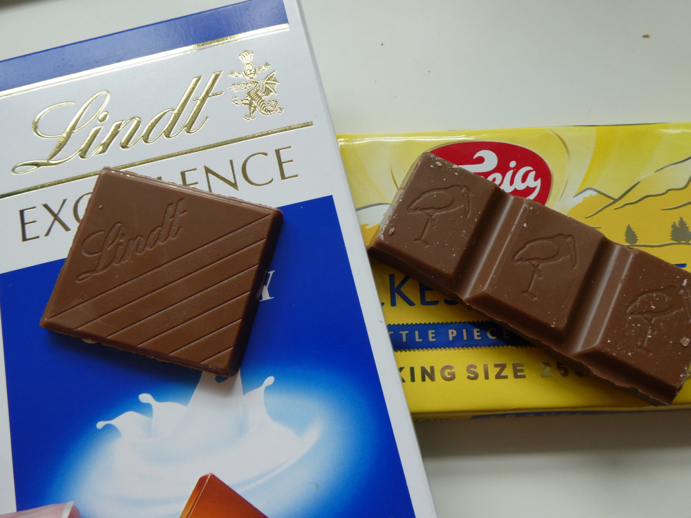 A square of Lindt chocolate lying on its blue and white box, next to ...